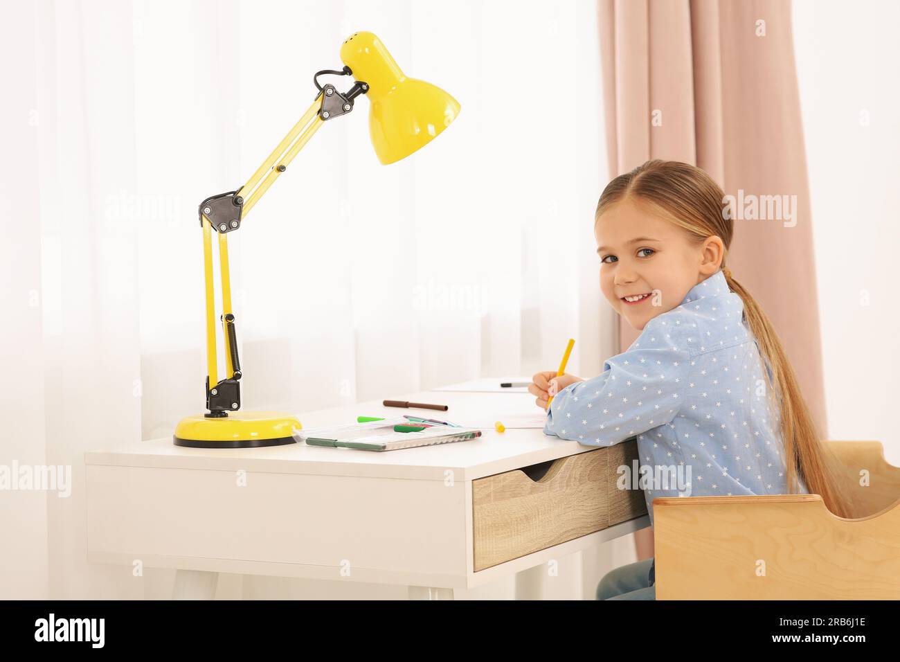Cute little girl drawing with marker at desk in room. Home workplace ...