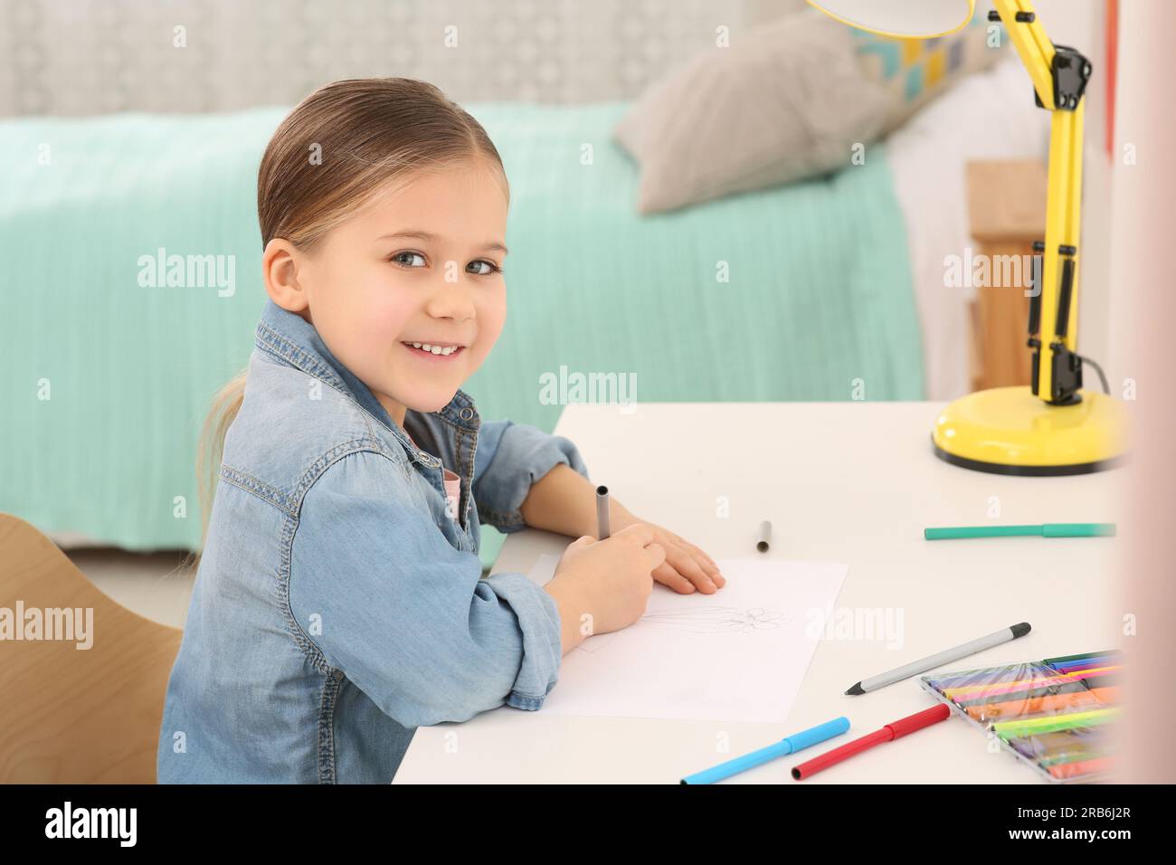 Cute little girl drawing with marker at desk in room. Home workplace ...
