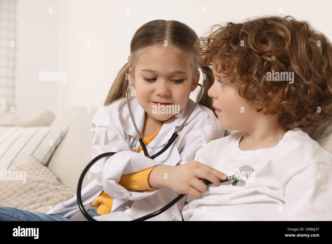 Little girl playing doctor with her friend at home Stock Photo - Alamy