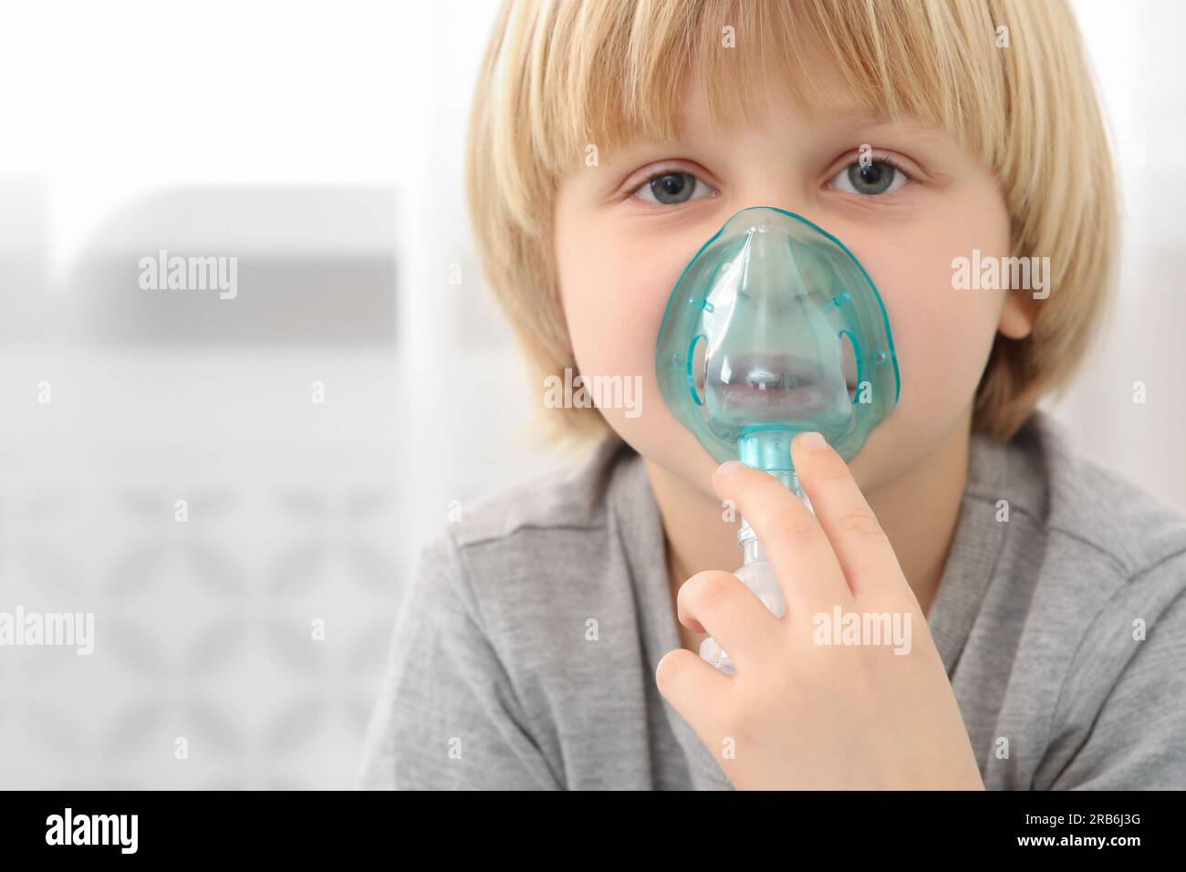 Sick little boy using nebulizer for inhalation indoors Stock Photo - Alamy