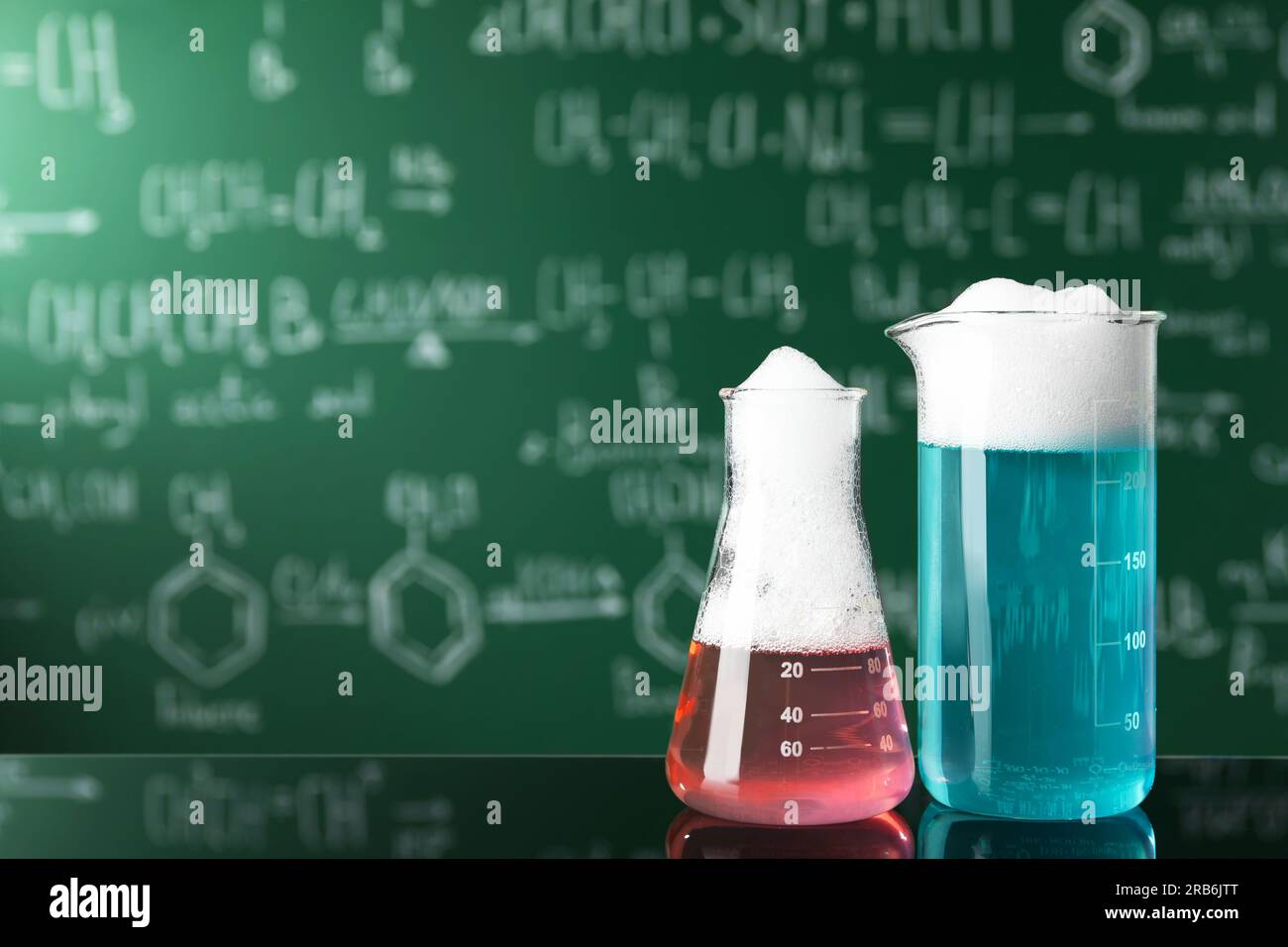 Laboratory glassware with colorful liquids on glass table, space for ...