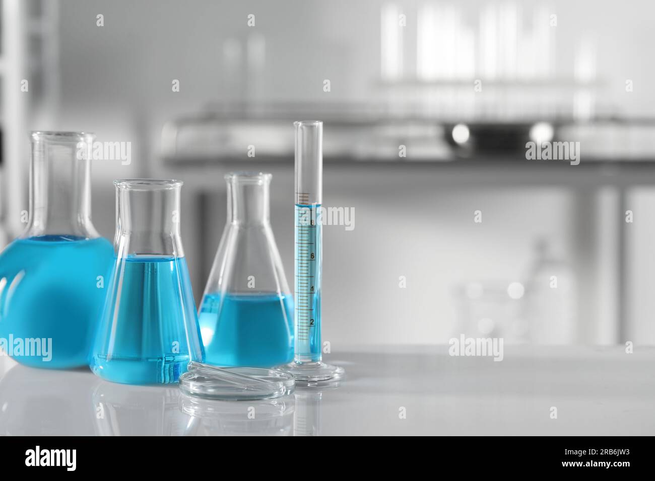 Different glassware with light blue liquid on table in laboratory ...