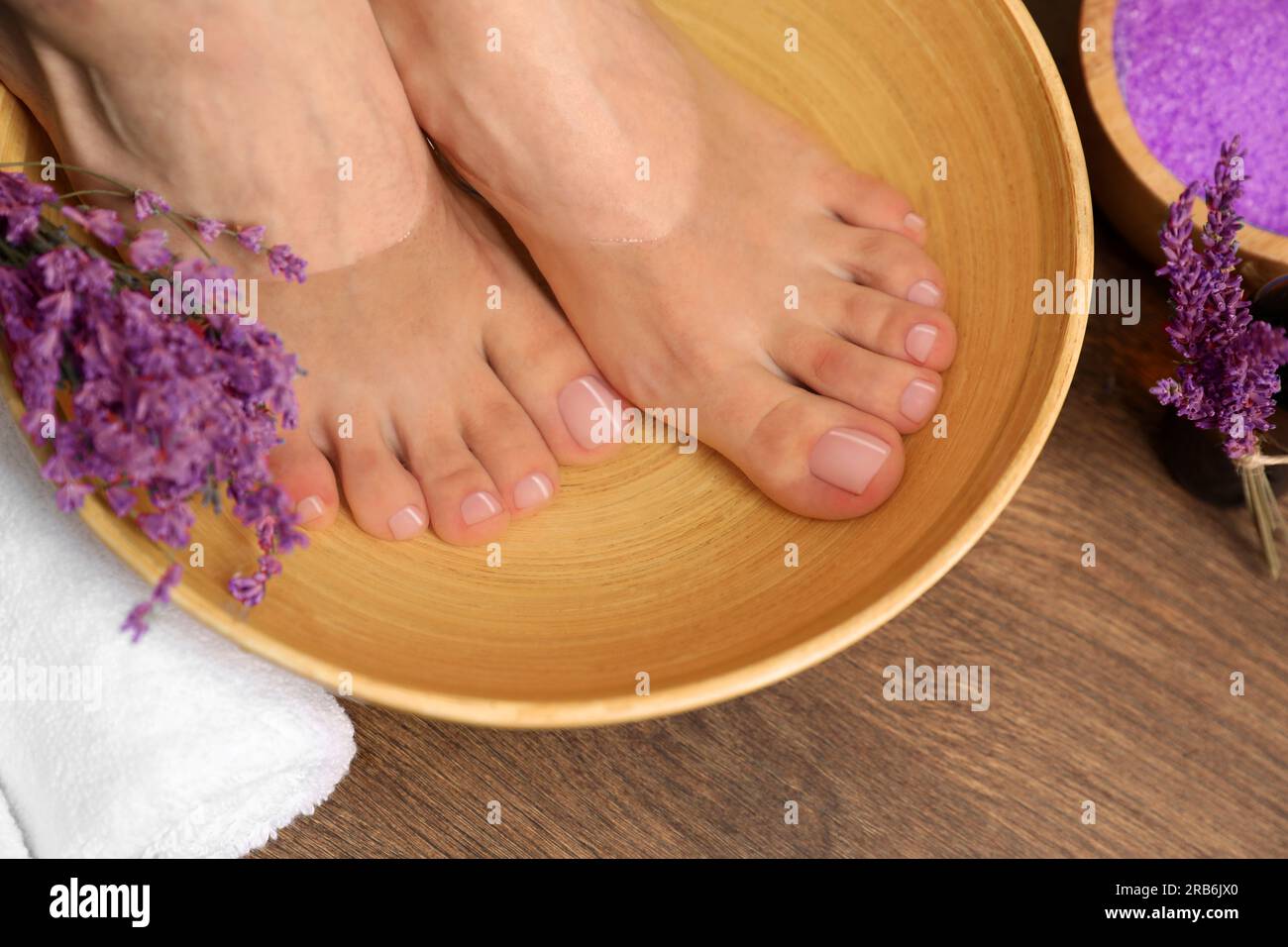 Woman soaking her feet in bowl with water and lavender, closeup ...