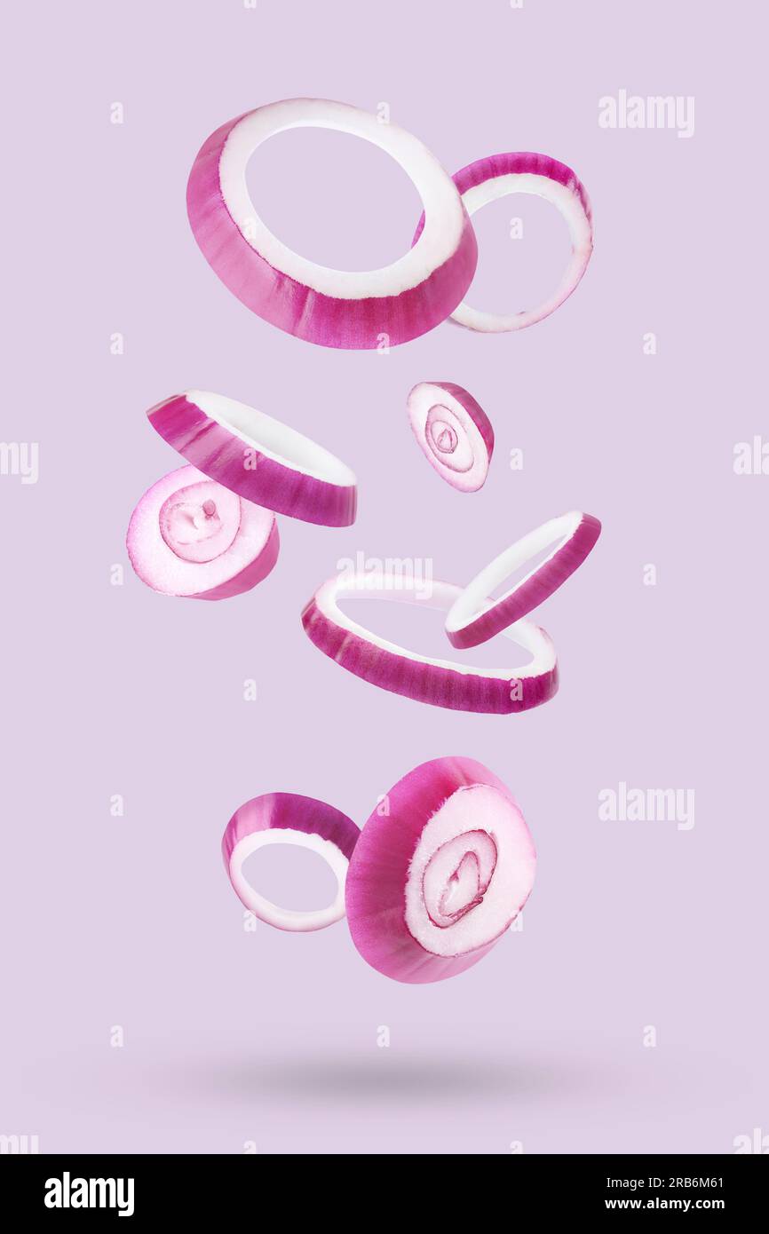 Fresh red onion rings falling on pale violet background Stock Photo - Alamy