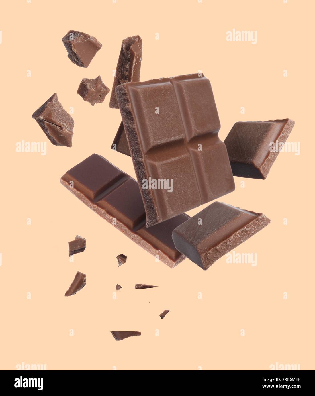 Pieces of chocolate bar falling on beige background Stock Photo - Alamy