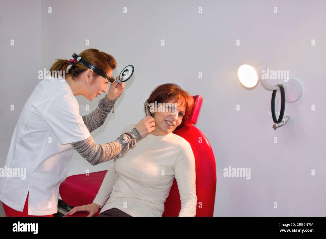 female doctor using a otoscope for an ear exam on an elderly patient ...