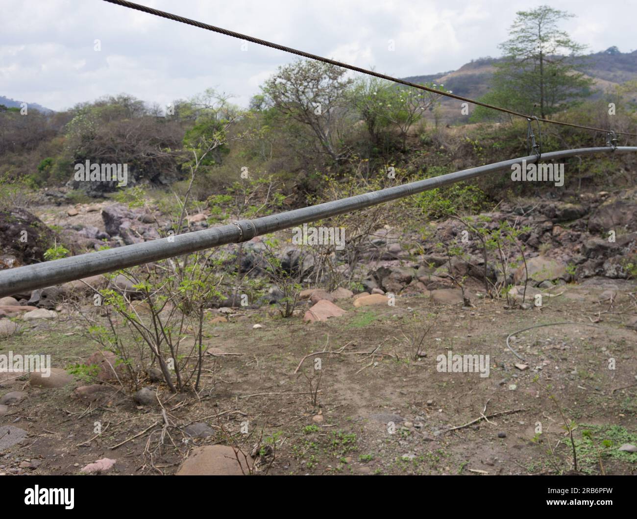 Water line and electric cable cross a dry river bed in rural Jinotega ...