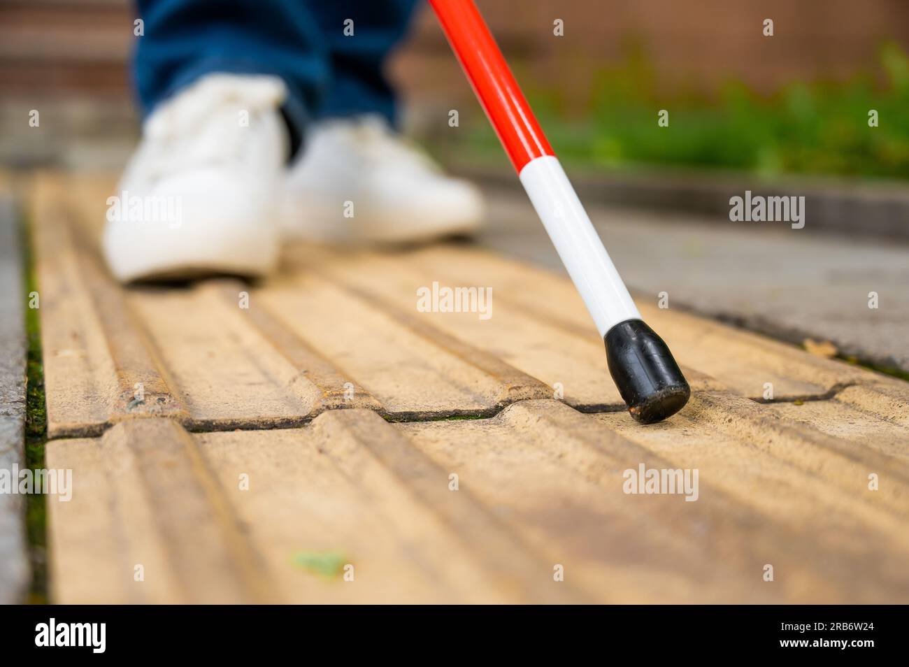 A blind woman walks on the street on tactile yellow tiles. Focus on the ...