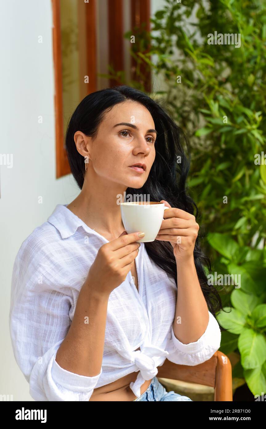 Portrait of smiling ukrainian woman drinking hot capuccino and looking ...