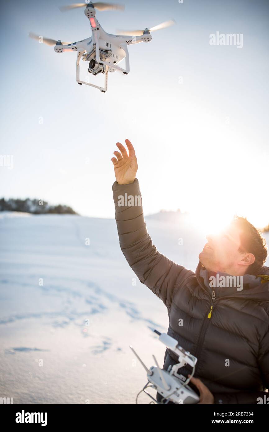 Young man controlling his drone in snowy outdoors. Drone operator ...