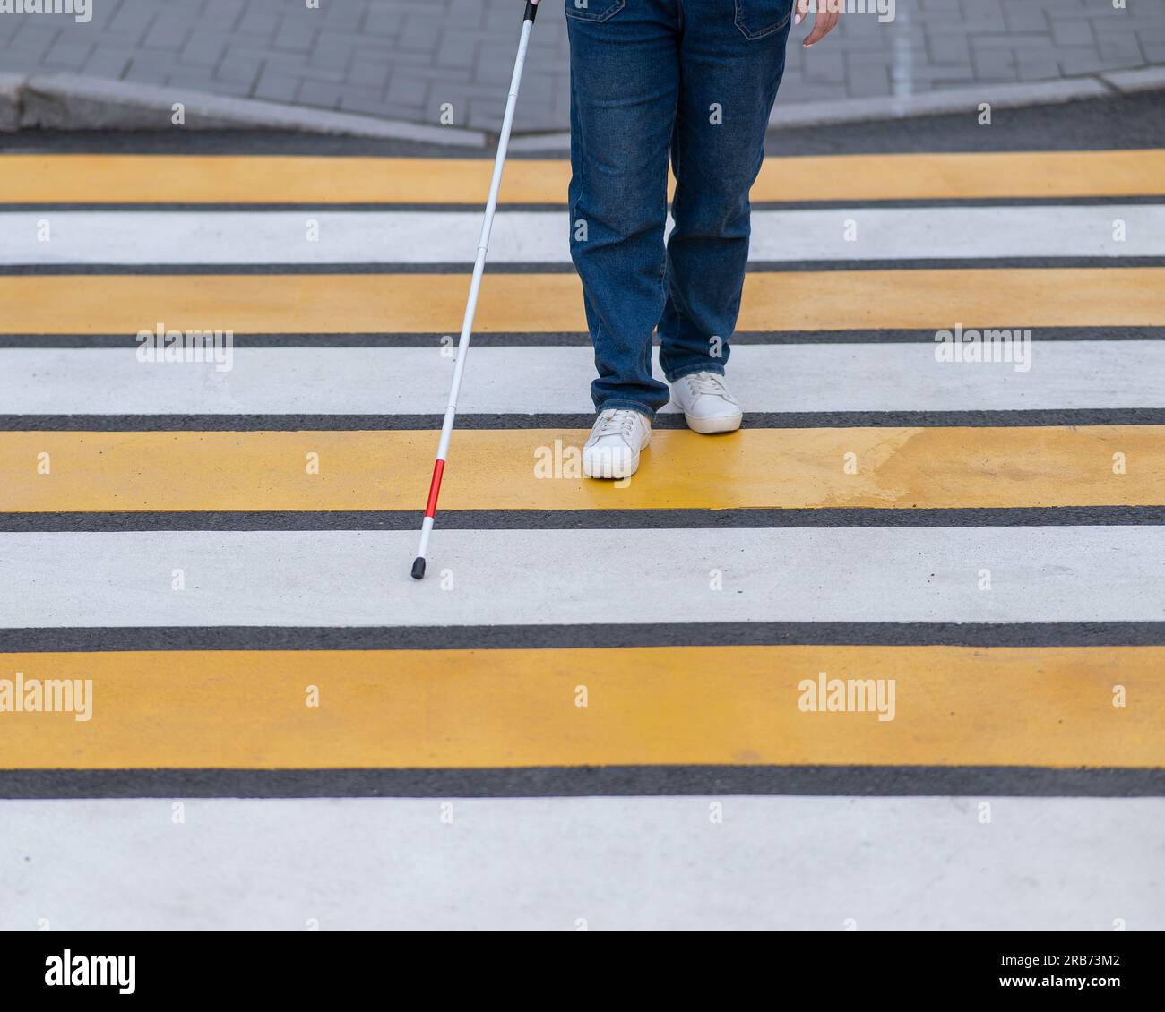 Close-up of the legs of a blind woman crossing the road at a crosswalk ...