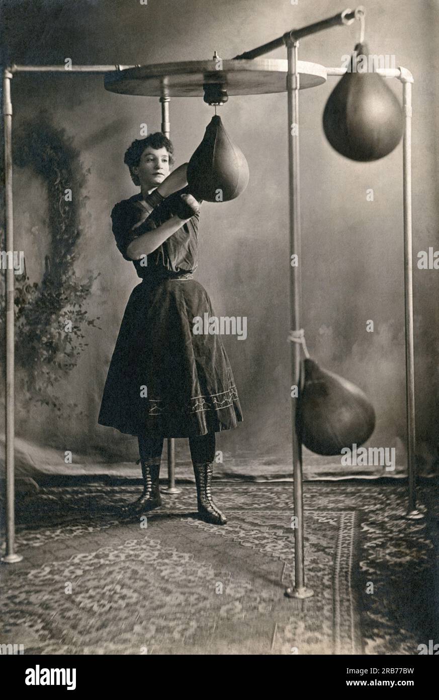 United States: c. 1890 A young woman in a skirt working out with boxing ...