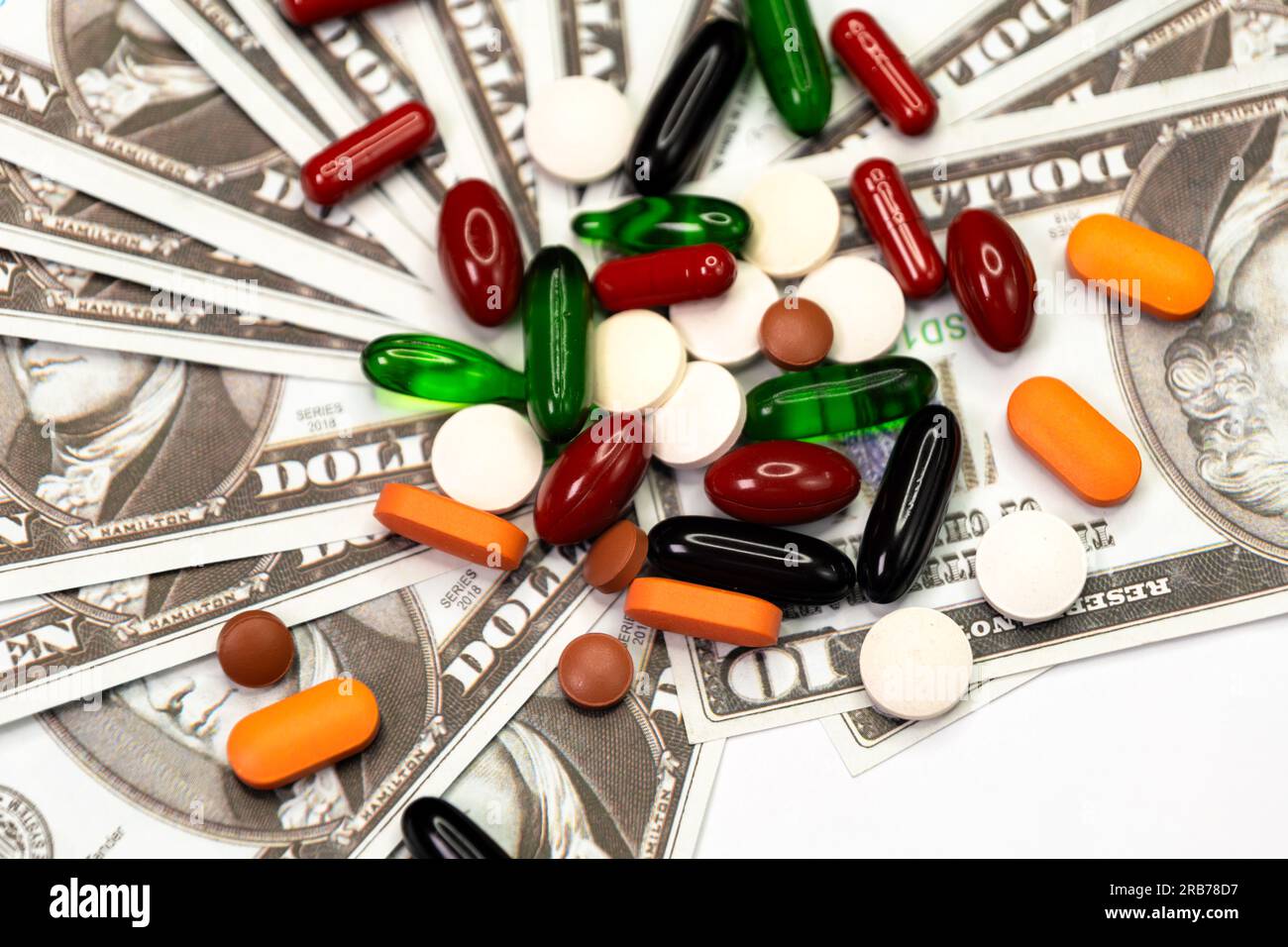 A close-up photo of colorful pills and a top on a ten-dollar bill in a ...
