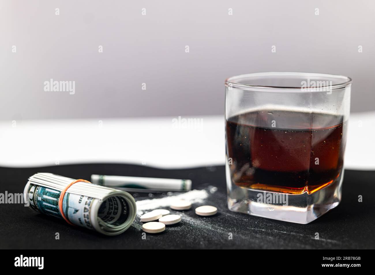 A photo of drugs, tablets, dollar bills, and alcohol in a glass on a ...
