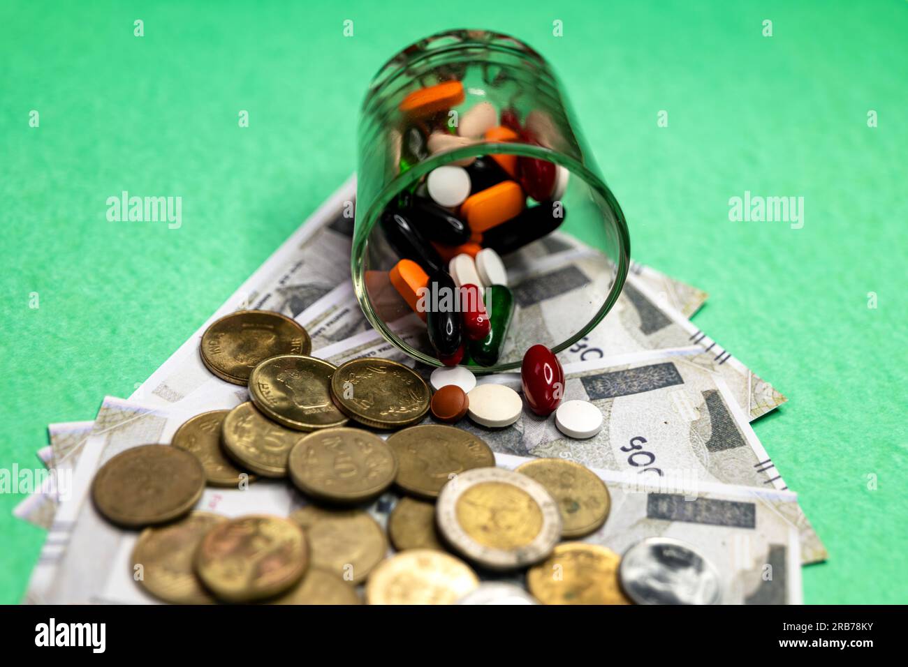 This image is about pills inside the glass below indian cash and coins ...