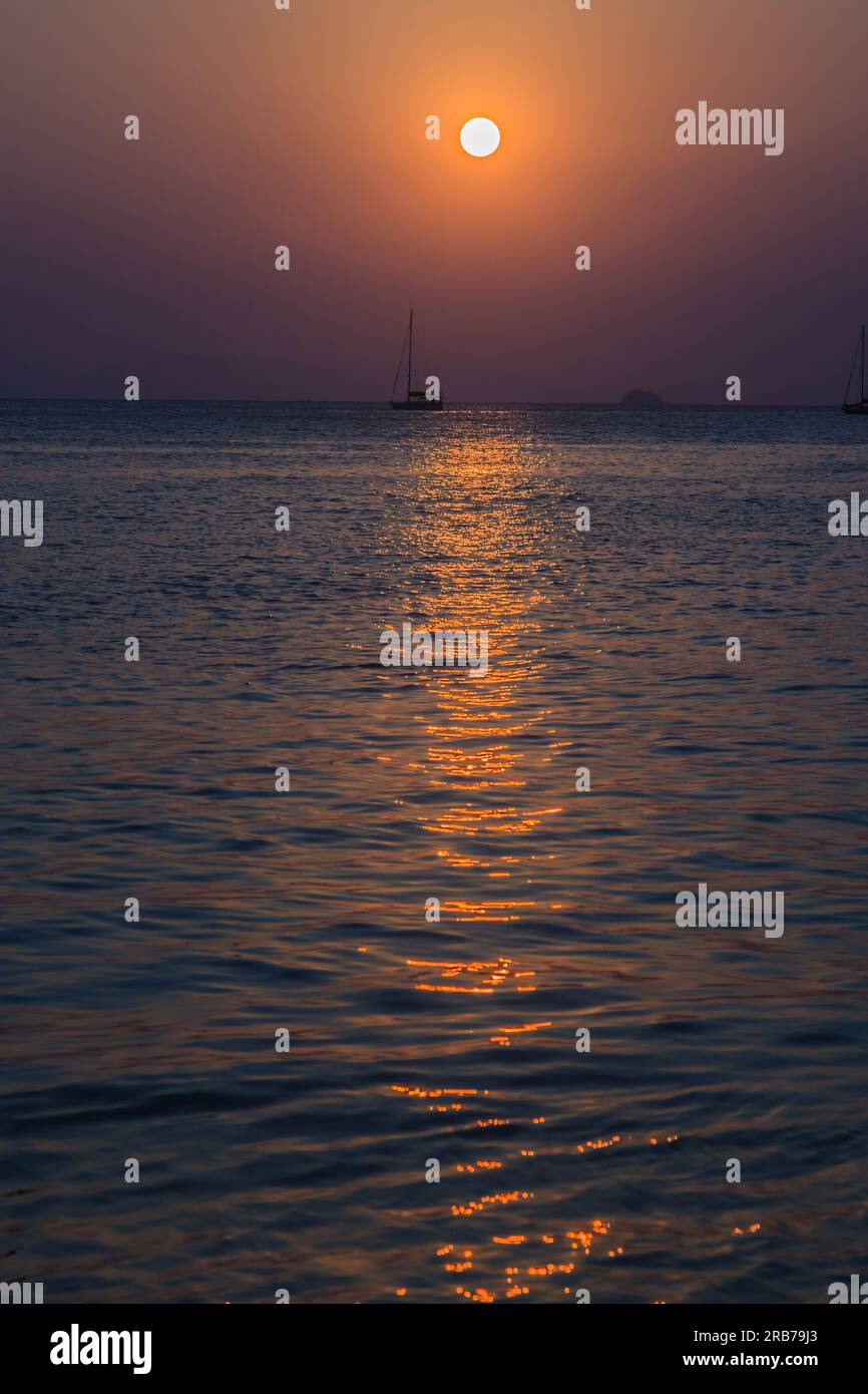 Photo of a sunset over the sea with a boat in backlight photographed ...