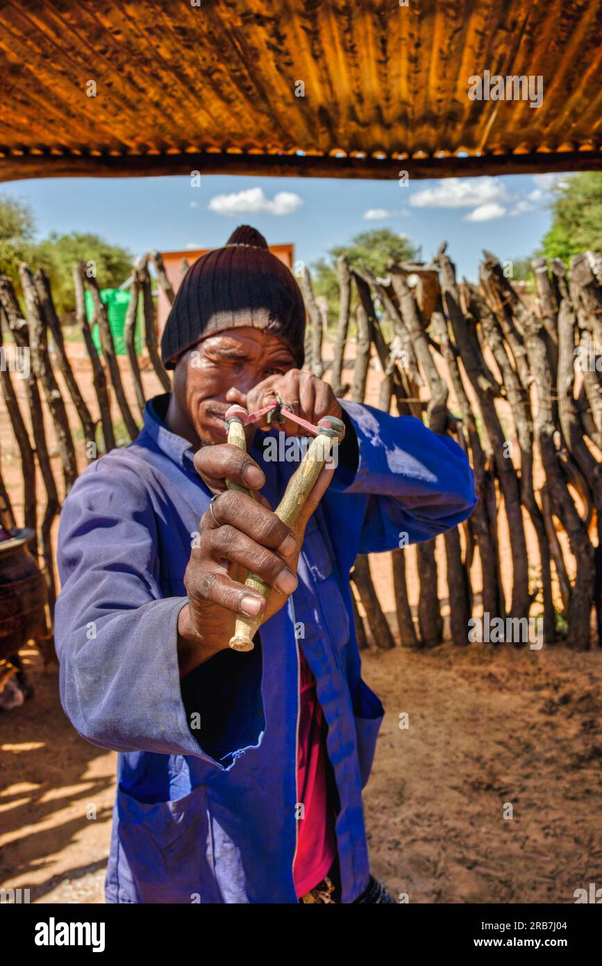 Portrait of an African village man aiming with a handcrafted slingshot ...