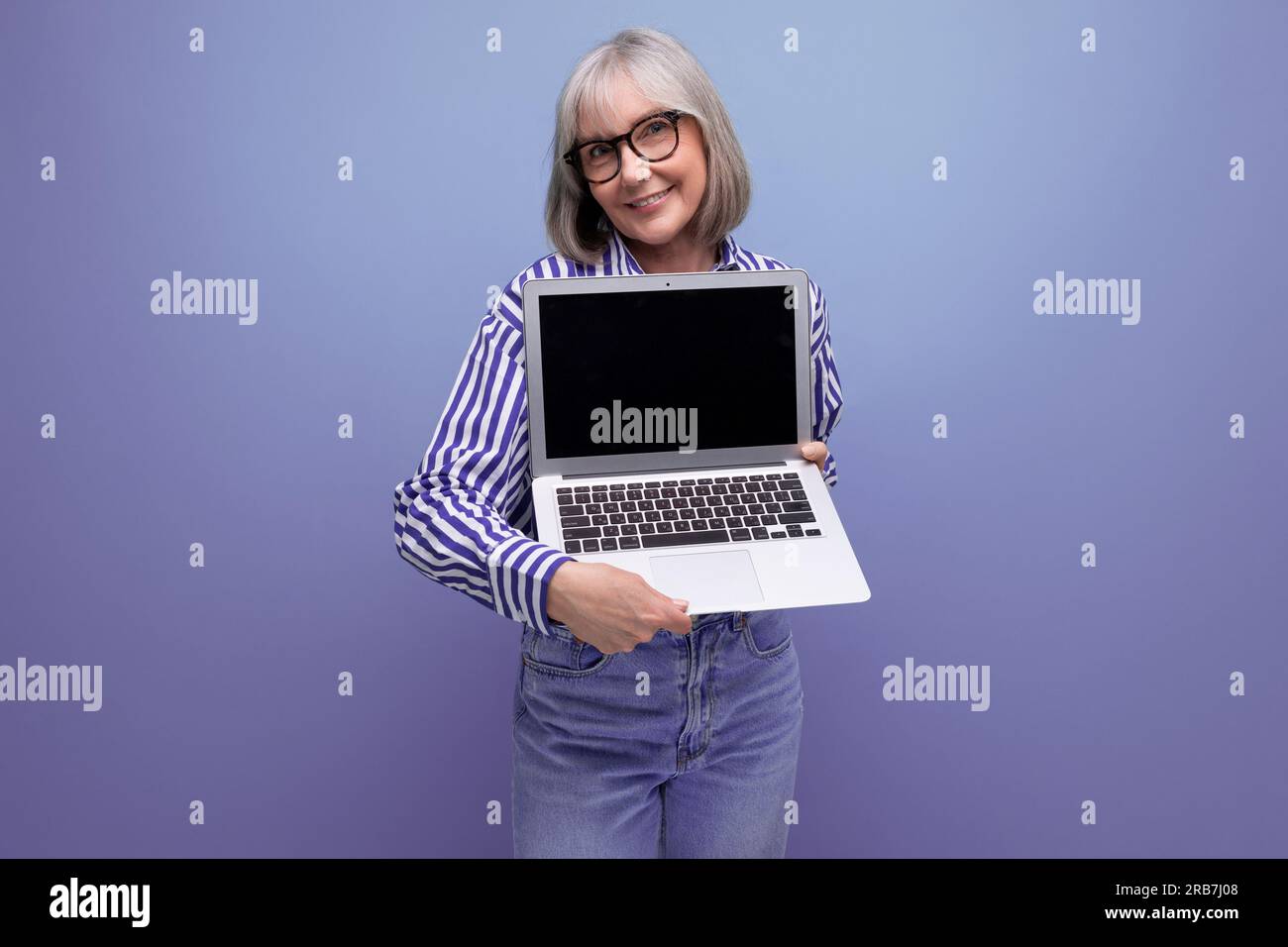 smiling 60s mature woman with gray hair with laptop mockup on bright ...