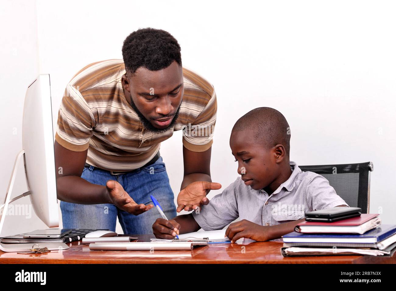 a young father in a T-shirt standing in office guiding his son to work ...