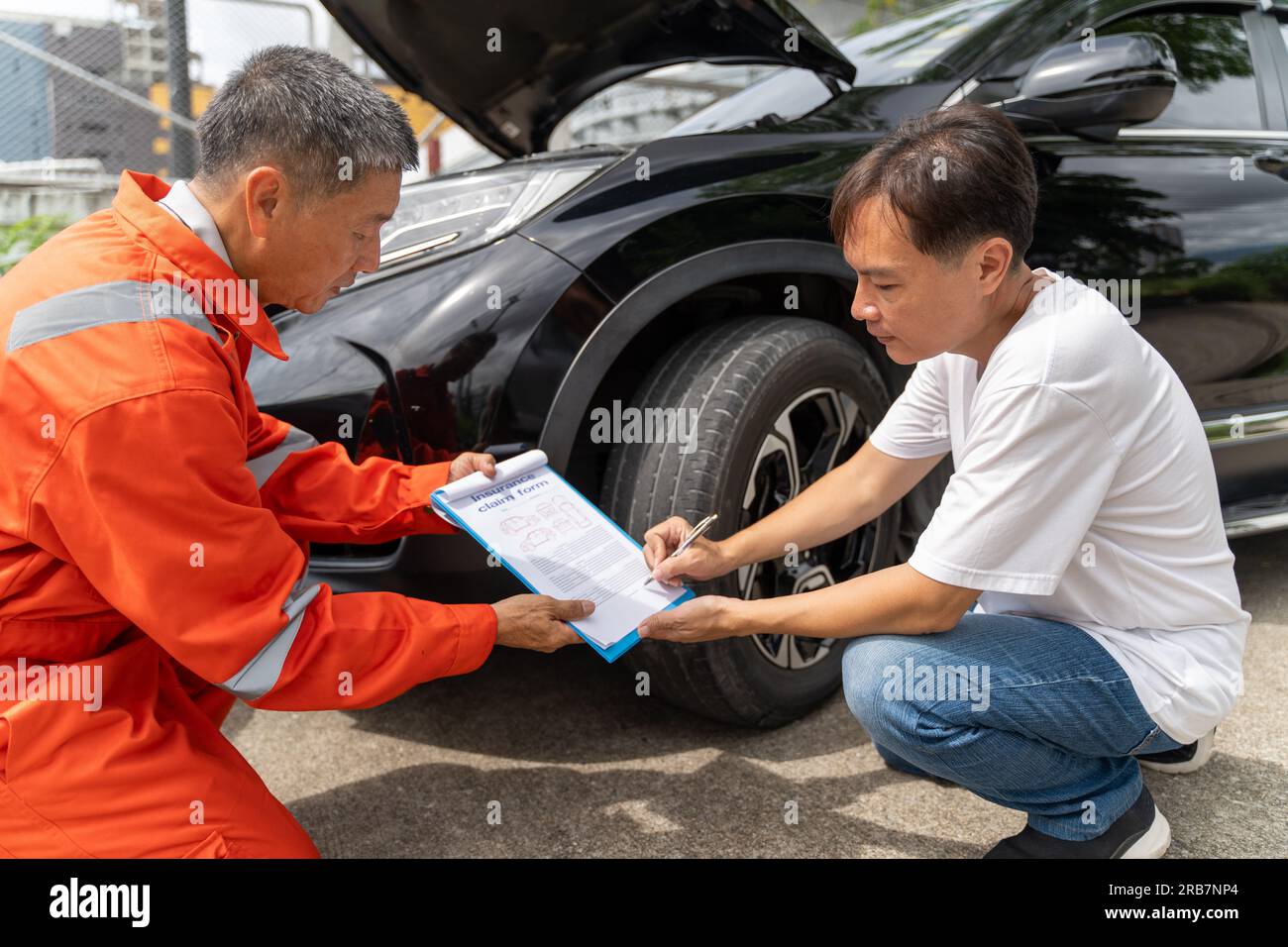 A car insurance agent showing the male customer where to sign the car ...