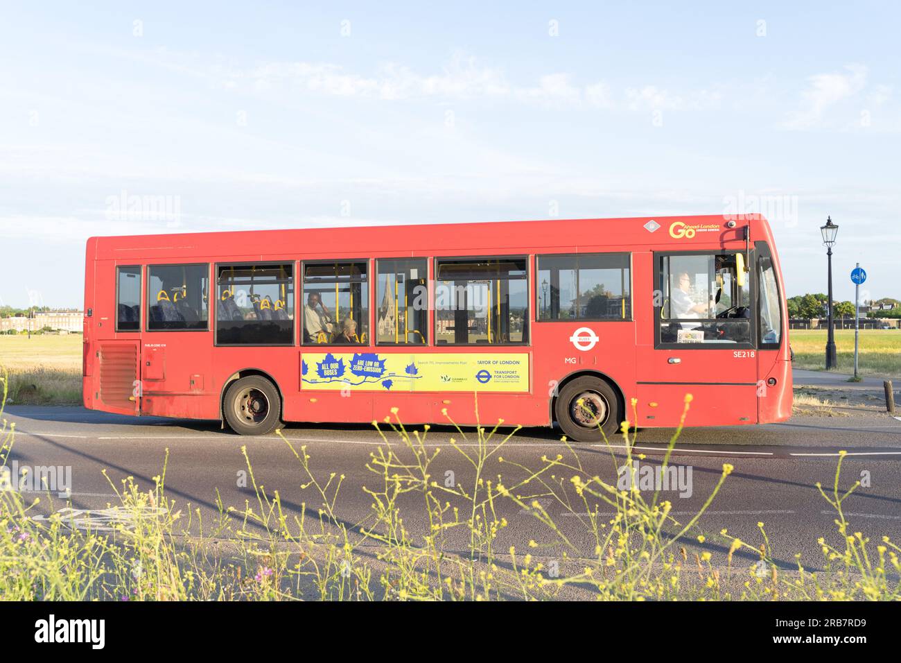 side view of London single decker red bus taking people home during ...