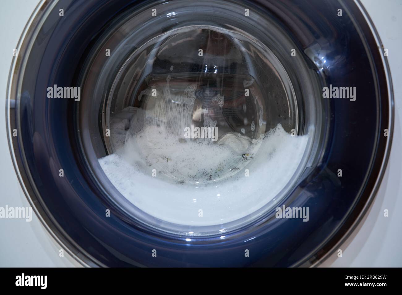 The round door from the washing machine is dark in color, with white ...
