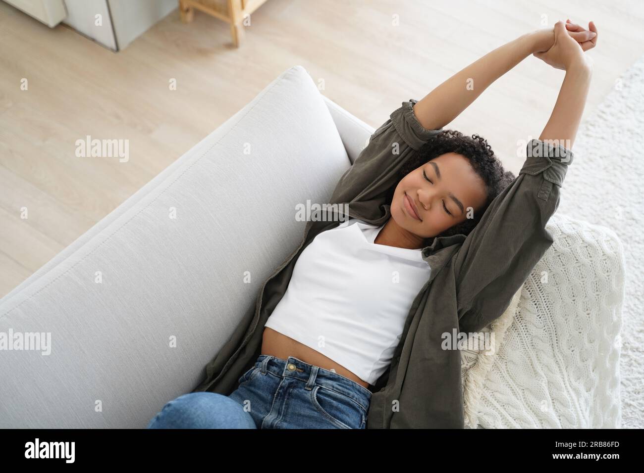 Relaxed girl stretches on cozy couch at home. Teen wakes up after nap ...