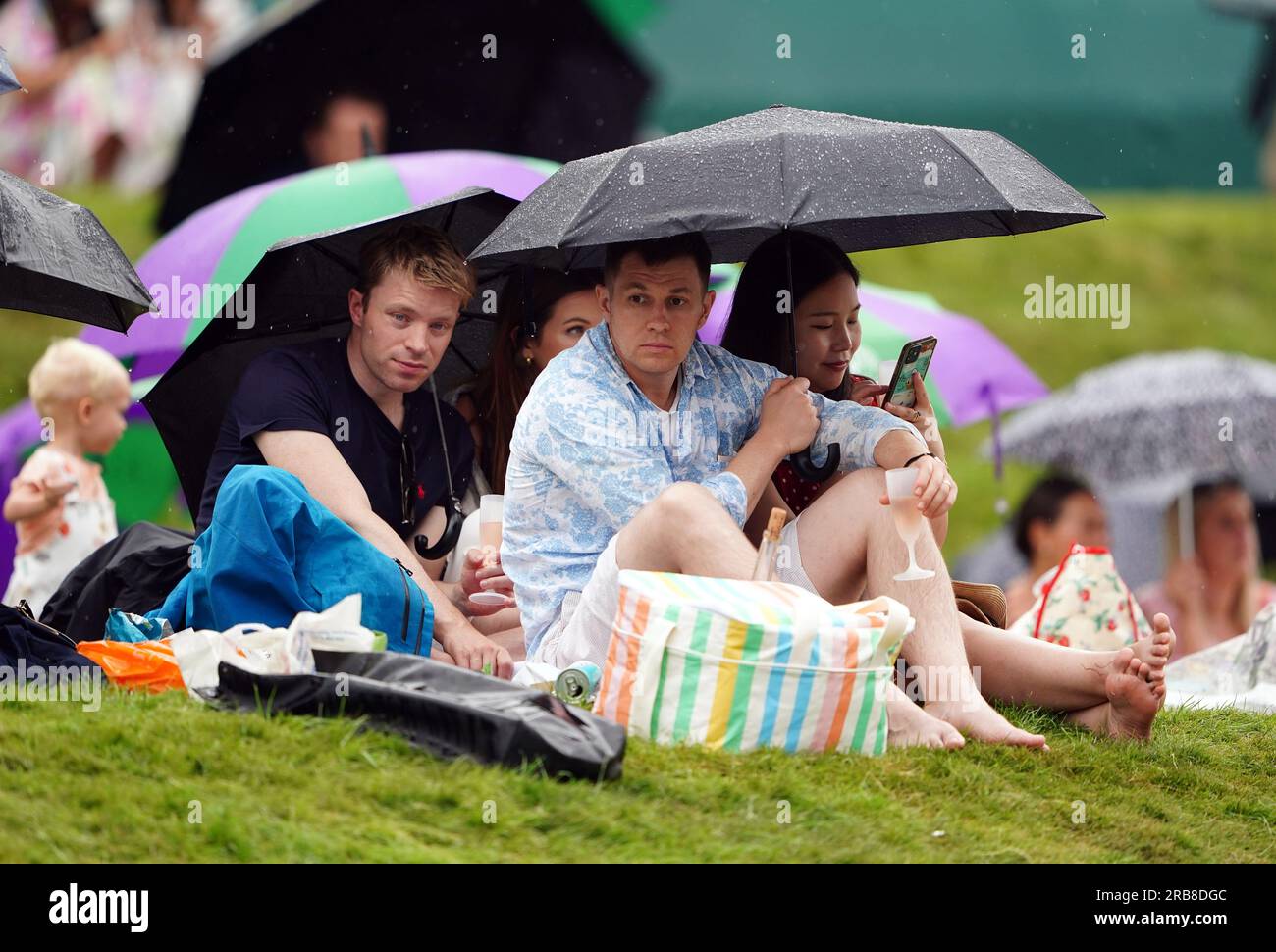 Spectators take shelter during a rain delay on day six of the 2023 Wimbledon Championships at ...