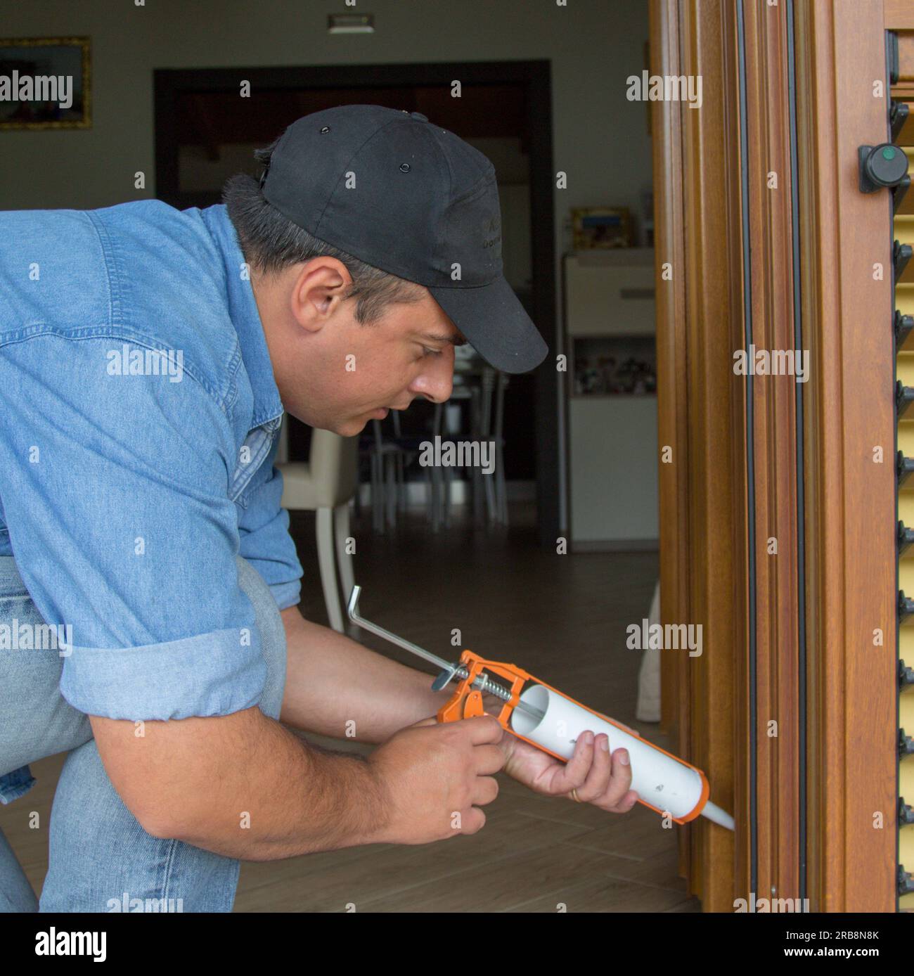 Image of a handyman who with a silicone gun closes the cracks in the ...
