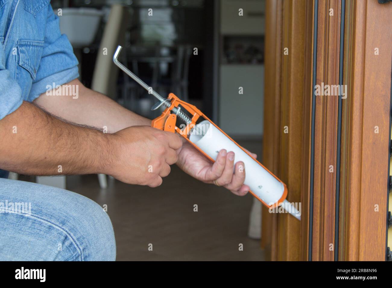 Image of the hands of a handyman who with a silicone gun installs and ...