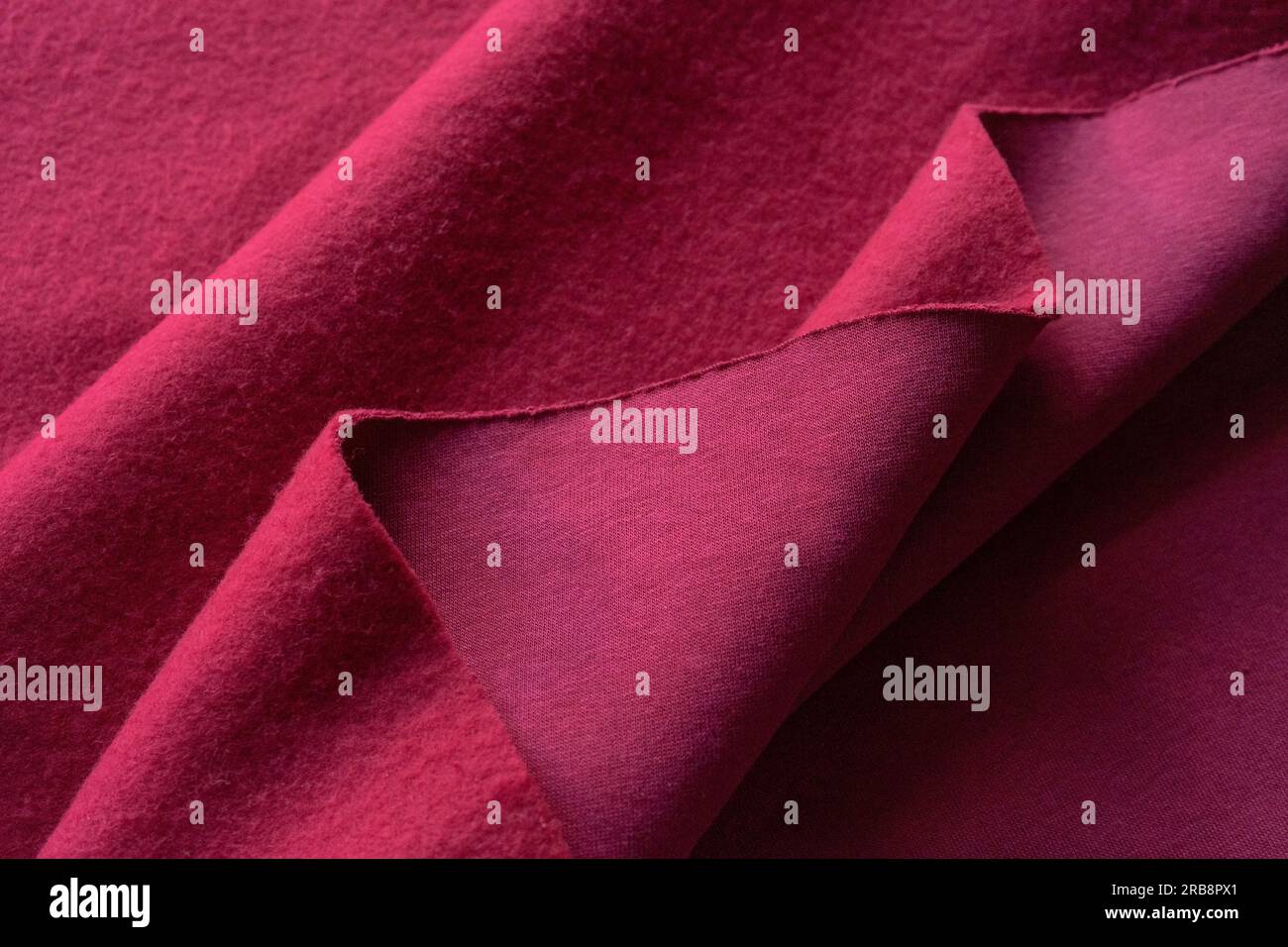 layers of French terry pink amaranth textile. A piece of fabric lies in ...