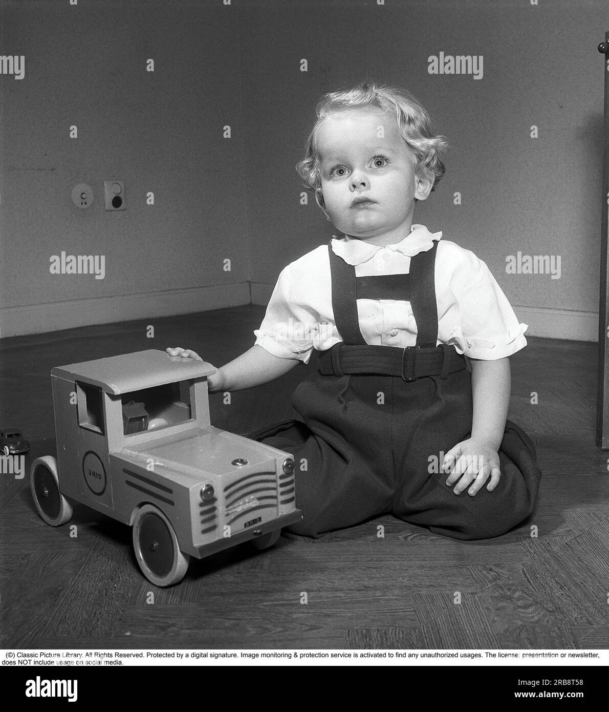 Children in the 1950s. A small boy sits neatly dressed and well-groomed ...