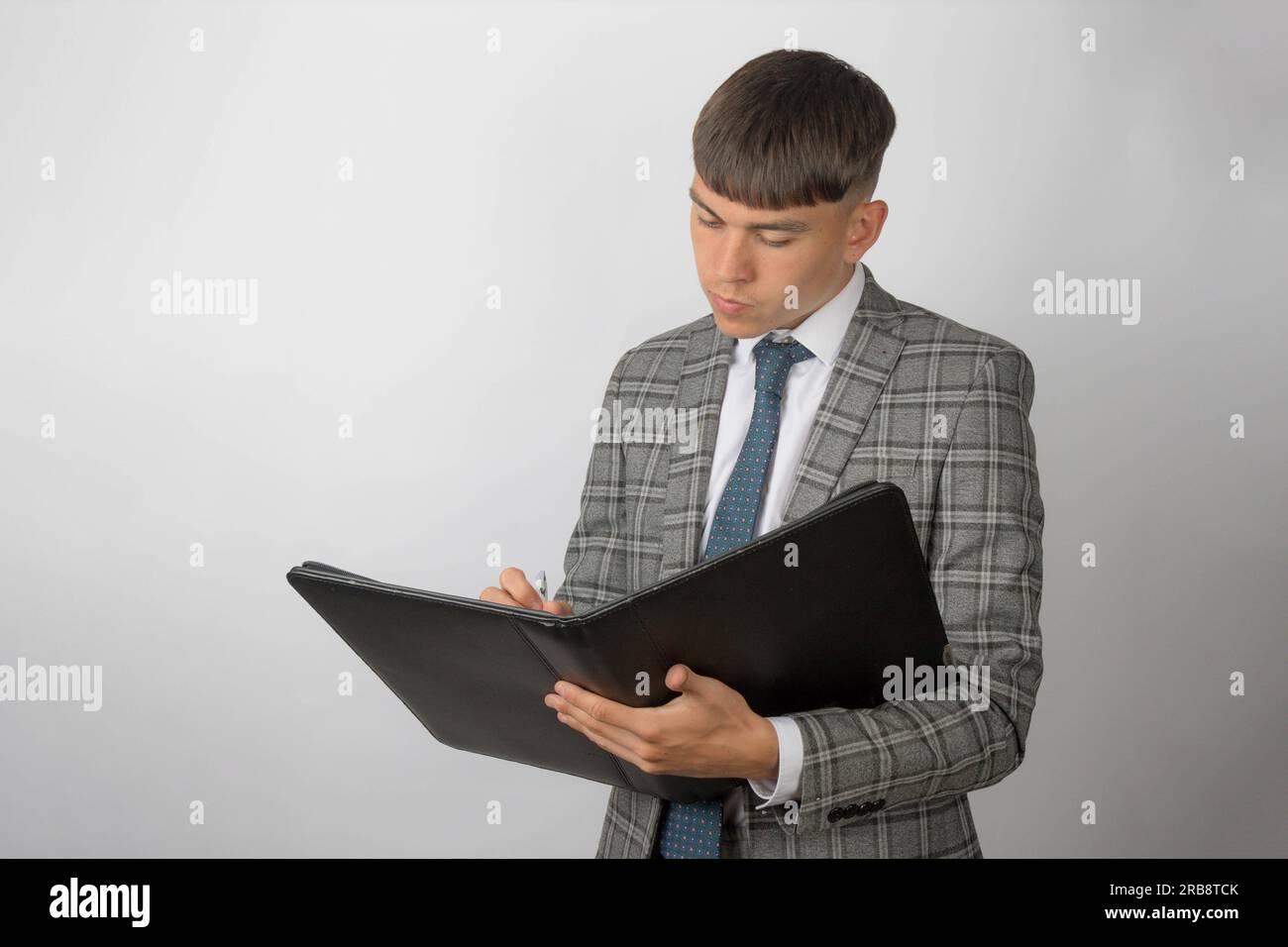 Young entrepreneur wearing a suit and tie writing in a folder Stock ...