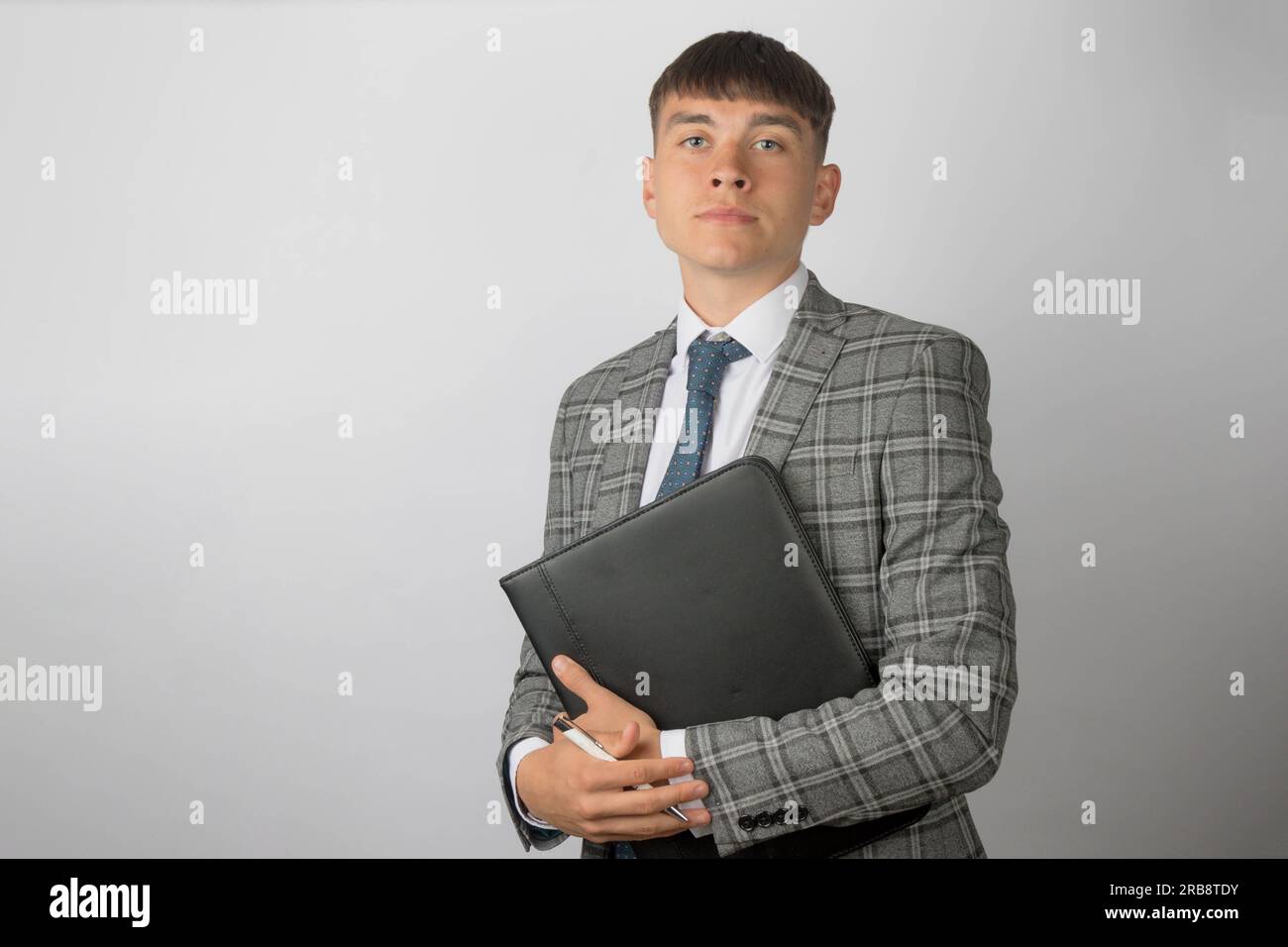 Young entrepreneur wearing a suit and tie holding a black folder Stock ...