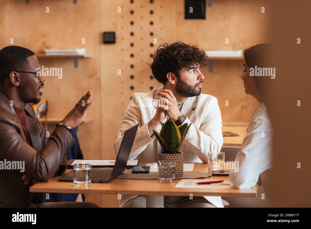 Three young and attractive work friends sitting together and talking at ...