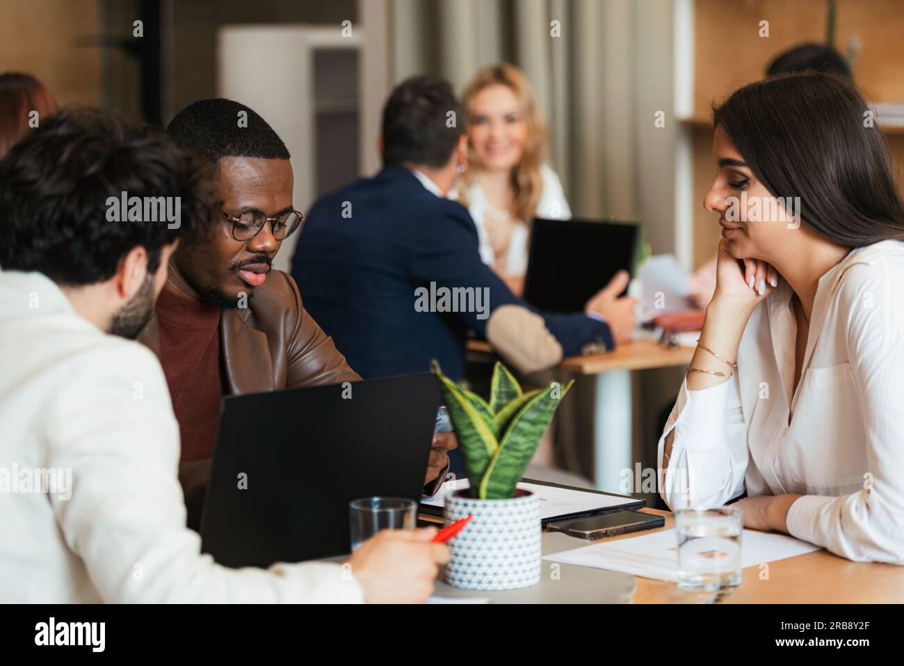 Three young and attractive work friends sitting together and working at ...