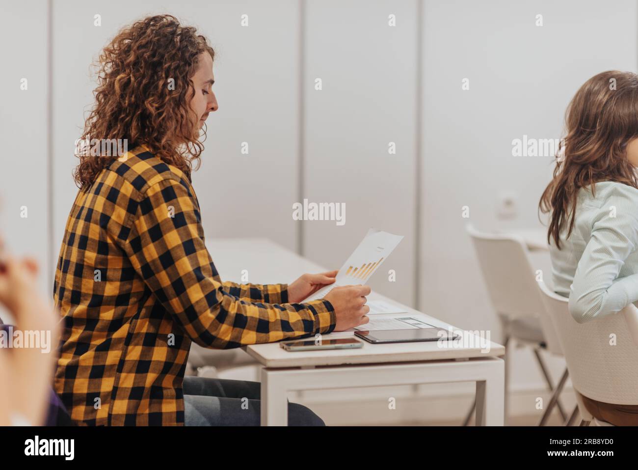 Side photo of long haired male employee reading sales report while ...