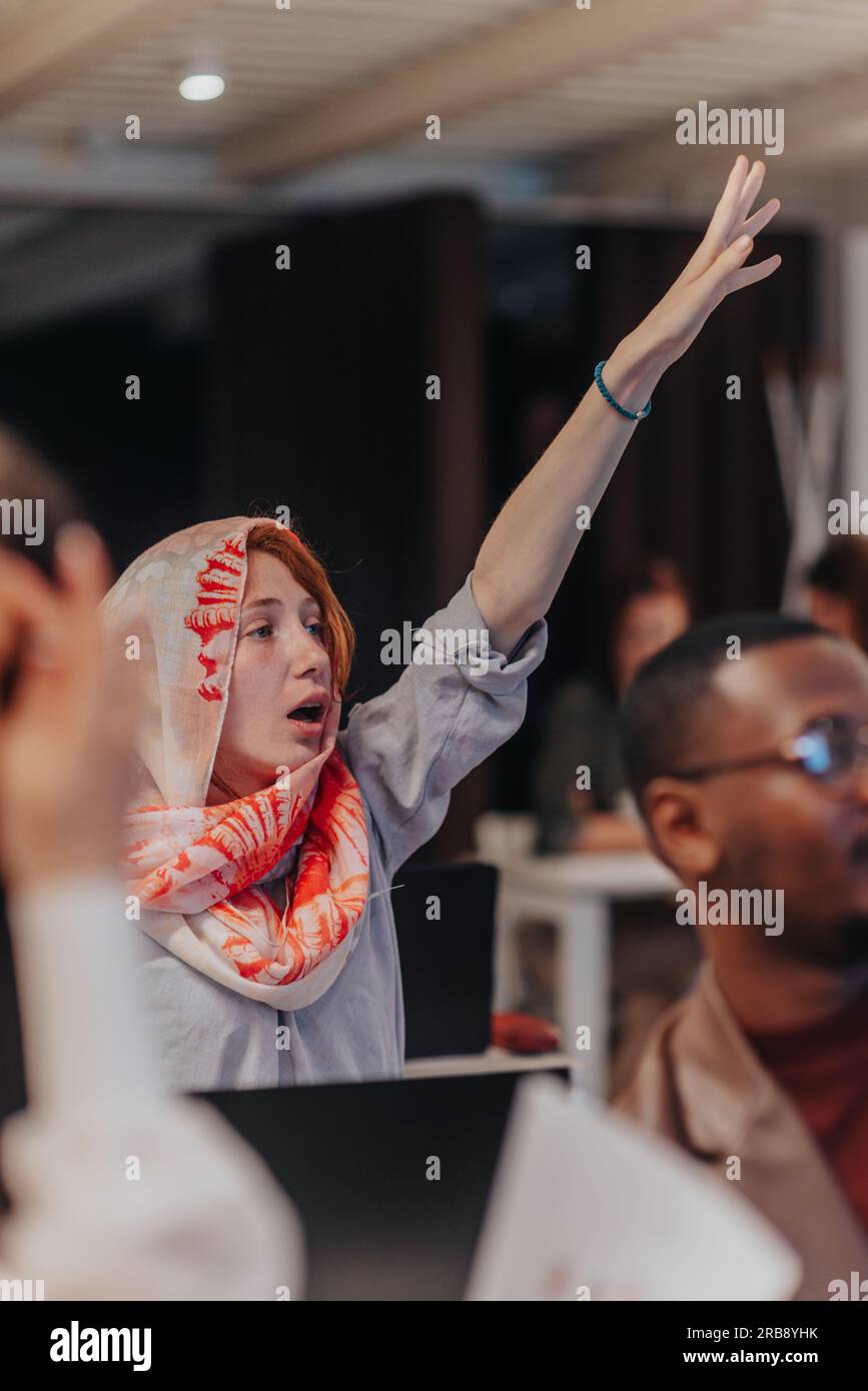 Ginger muslim woman raising hand to ask question during training at ...