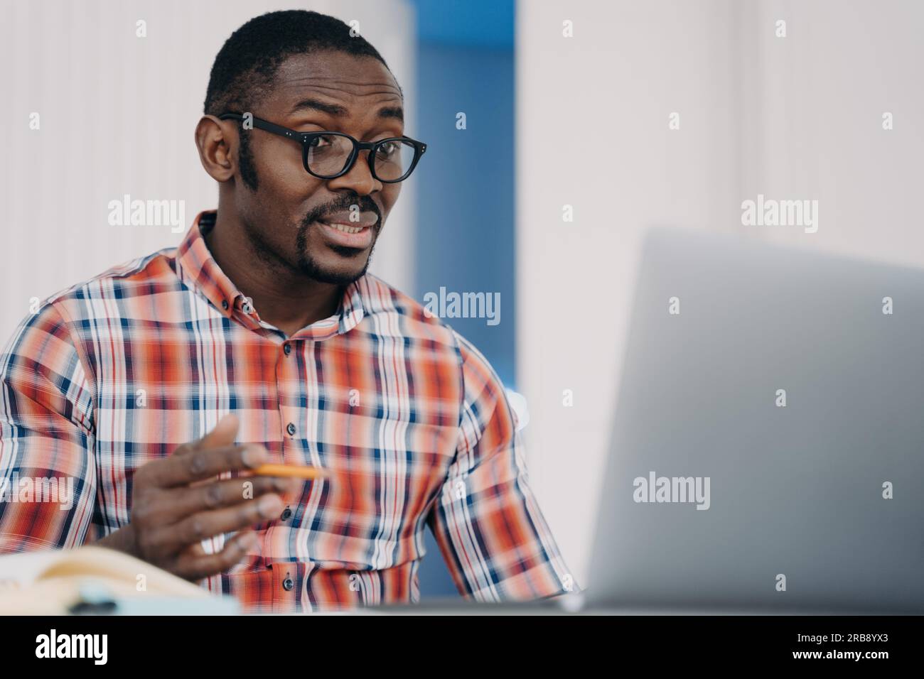 Puzzled african american employee in glasses looking at laptop screen ...
