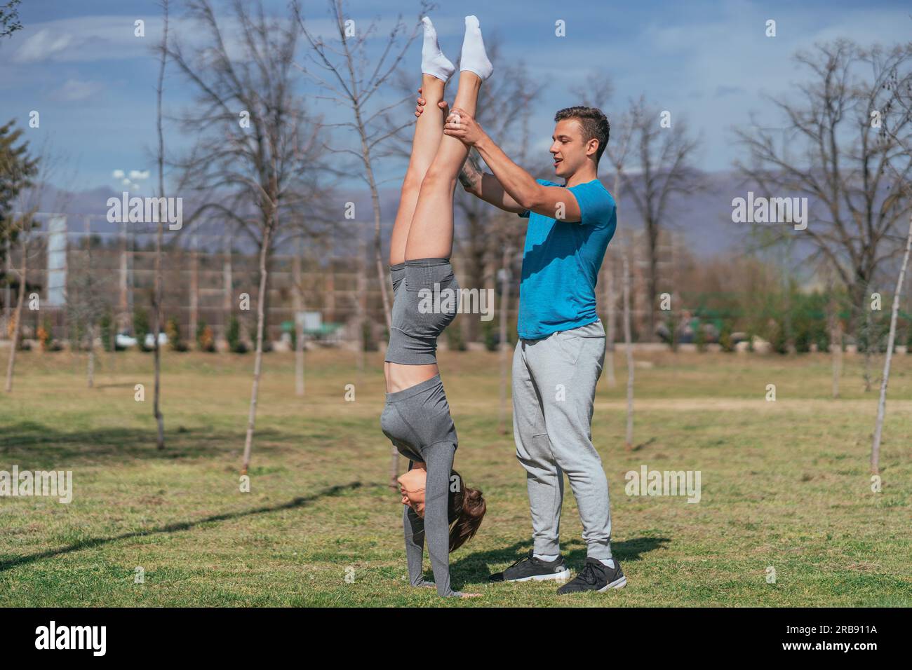 Good looking male sports person holding his female friend legs while ...