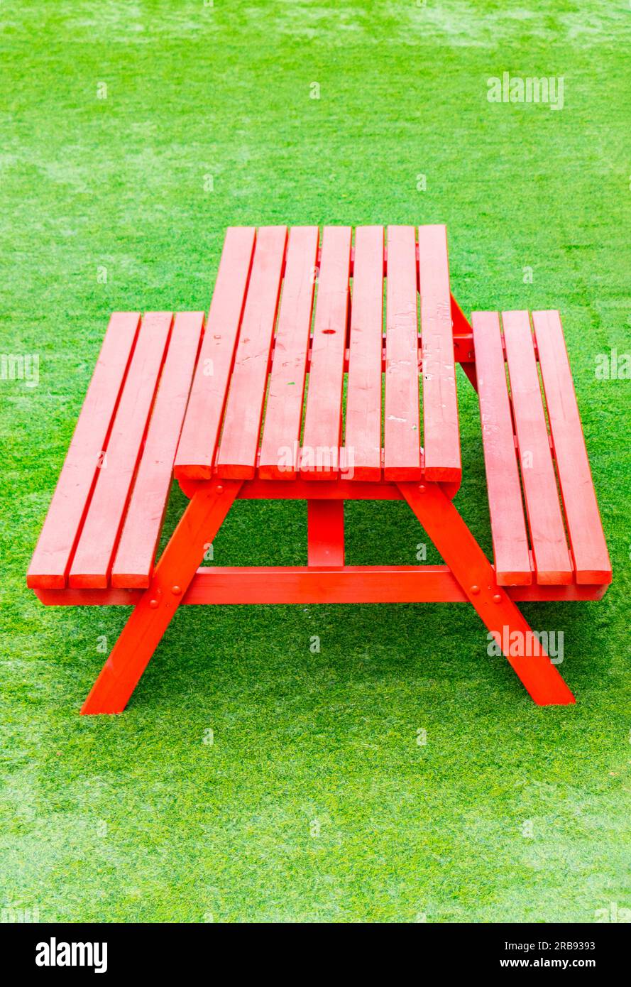 concept isolated red picnic bench on bright green artificial grass ...