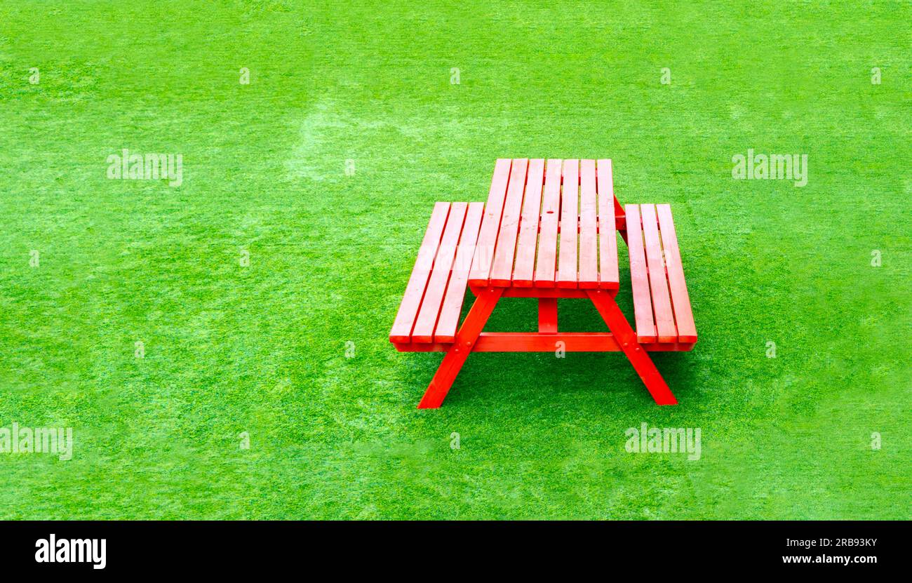 concept isolated red picnic bench on bright green artificial grass ...