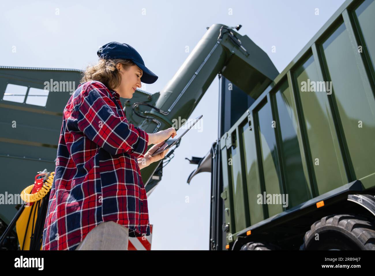 Woman farmer with tablet watching grain loading Stock Photo - Alamy