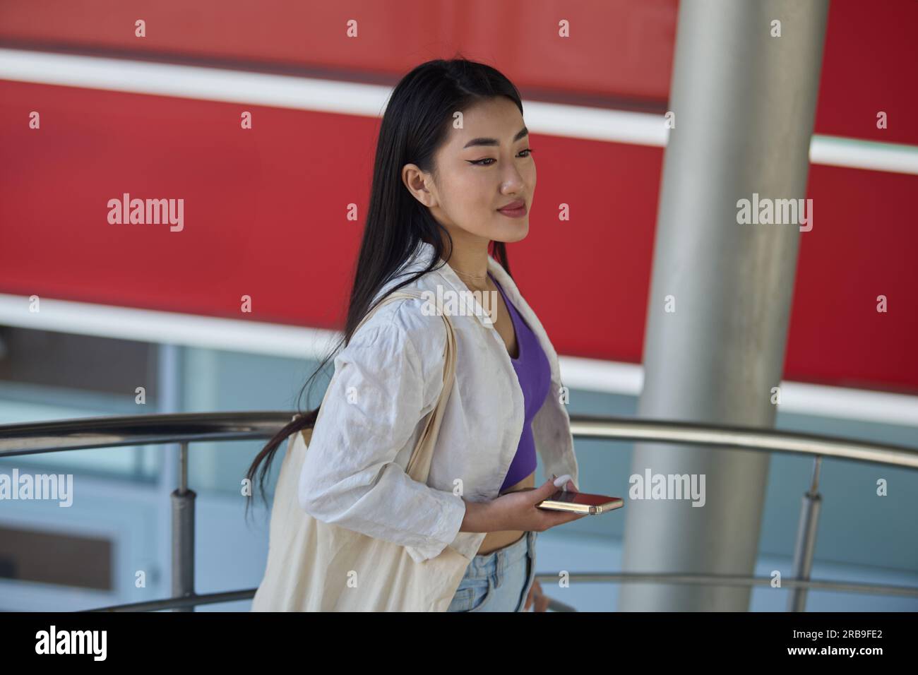 Beautiful Vietnamese woman in 20s walking up the stairs at the mall ...
