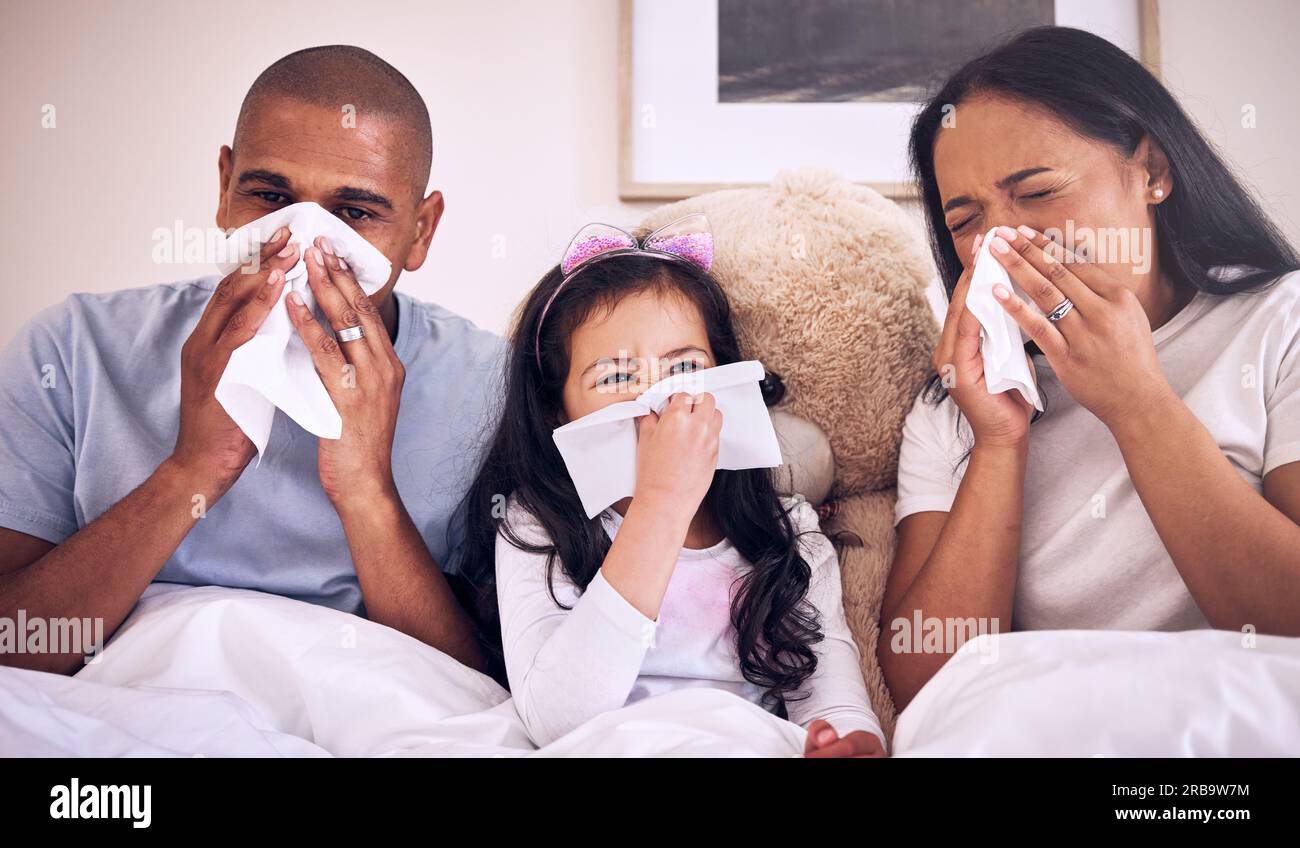 Family, sick and blowing nose on a bed together in a bedroom with ...