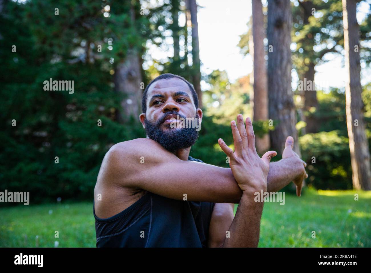 A concentrated athlete performs an arm stretch exercise to increase his ...