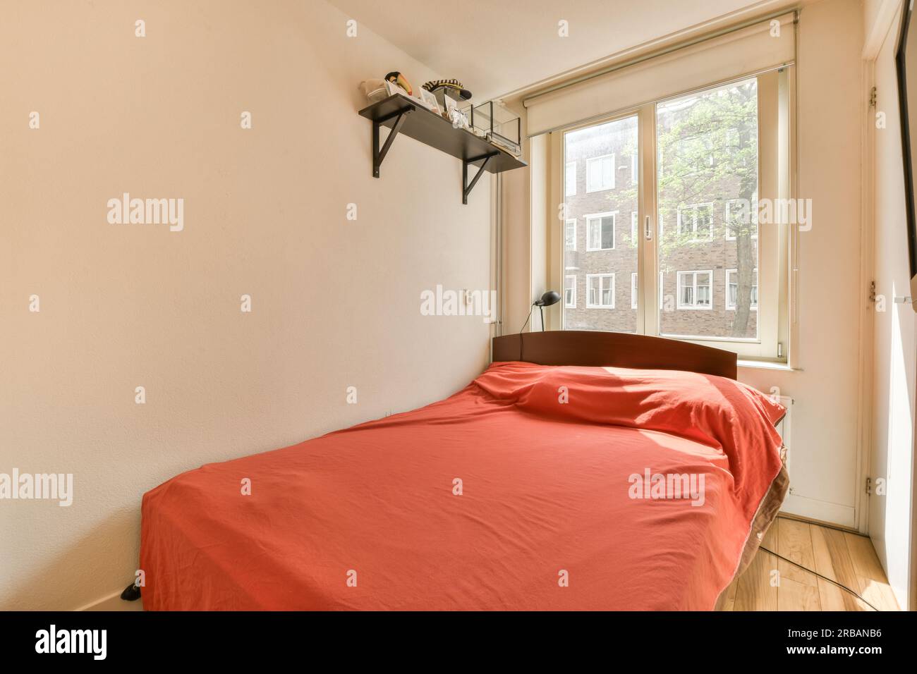 a bedroom with a red bed cover on it's headboard and windows in the ...
