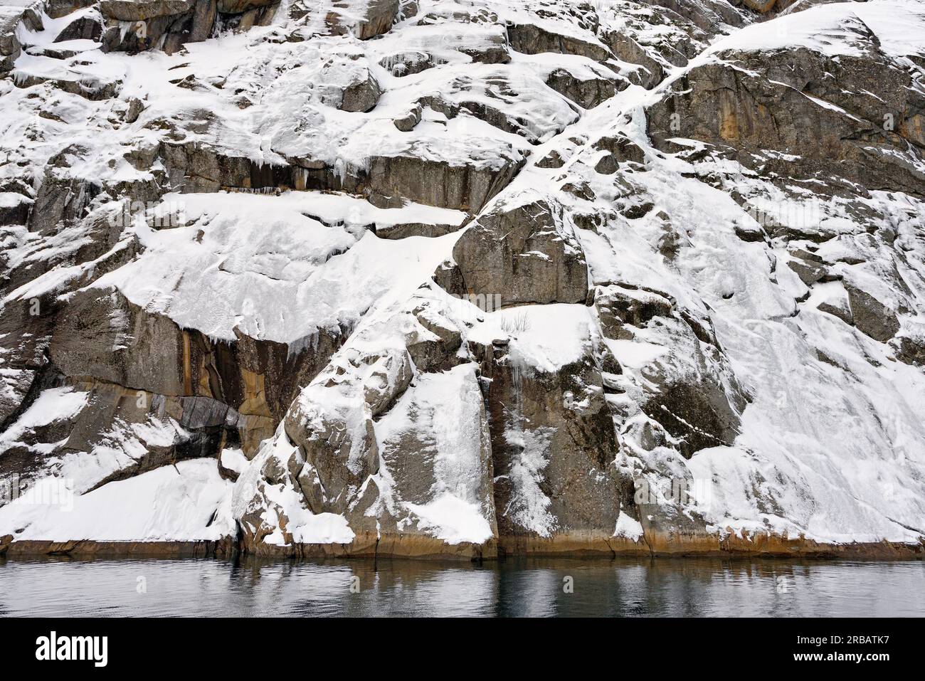 Rock face, granite, partly covered with snow and ice, Trollfjord ...