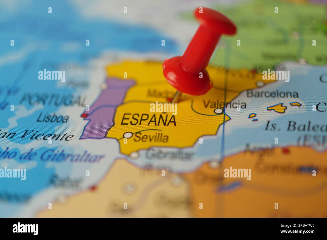 Spain marked with a red thumbtack on a map with an out-of-focus ...