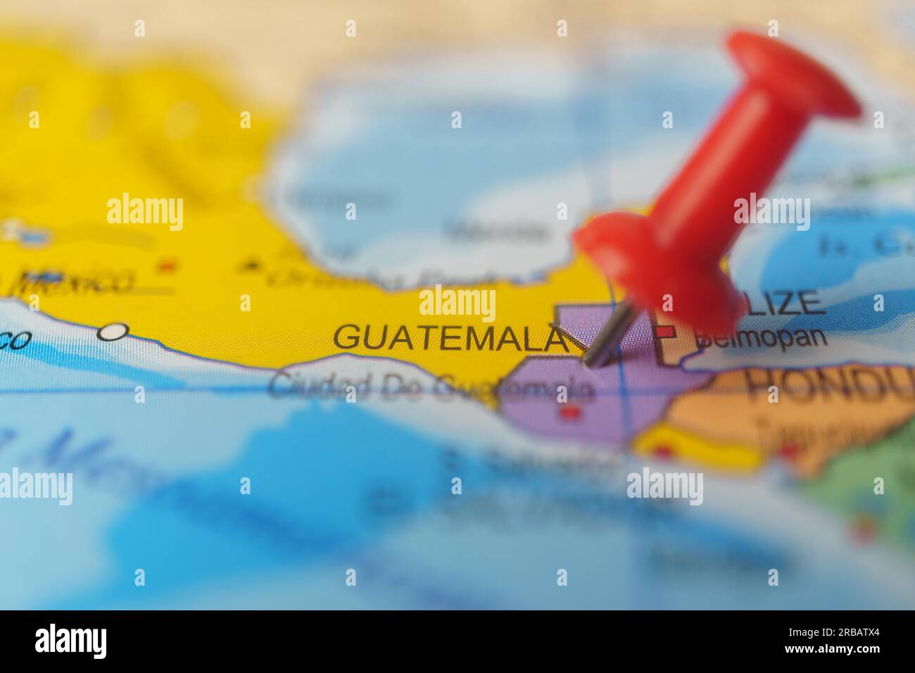 Guatemala marked with a red thumbtack on a map with an out-of-focus ...